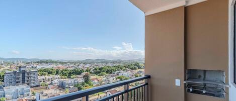 Uma varanda com vista para a paisagem urbana, incluindo edifícios e áreas verdes.