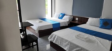 Quarto de hotel com duas camas, uma mesa e uma cadeira.