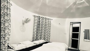 Um quarto com uma cama, cortinas, um espelho e uma porta.