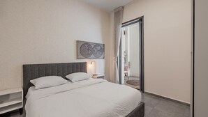 Quarto moderno com uma cama grande, uma mesinha de cabeceira com abajur e uma pintura de mapa mundi na parede.