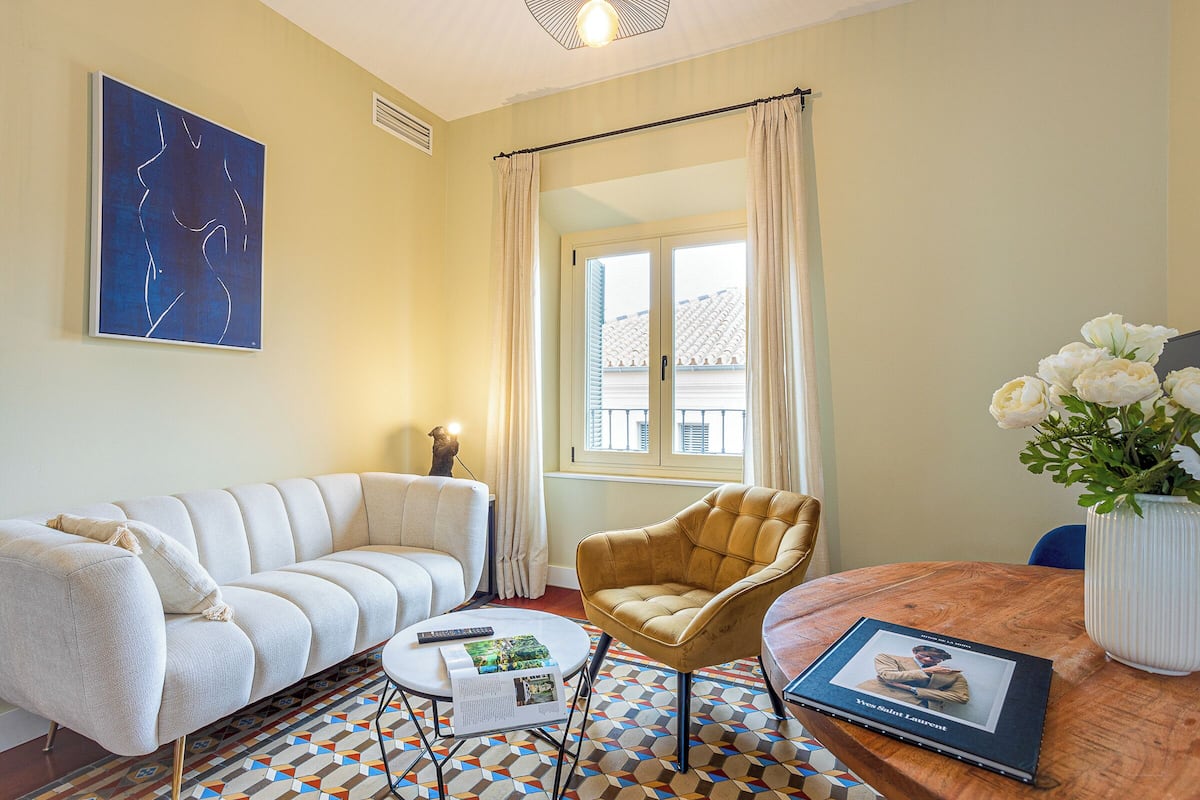 Uma sala de estar com sofá, poltrona, mesa de centro e uma fotografia emoldurada sobre a mesa.
