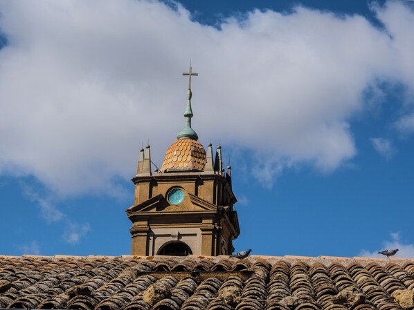 Uma igreja com cruz no topo, um relógio e um telhado em azulejos.