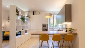 Cozinha moderna com ilha central, banquetas e nichos com plantas.