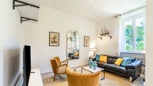 Uma sala de estar moderna com televisão de tela plana, um sofá com almofadas coloridas, uma poltrona e uma mesa de centro.