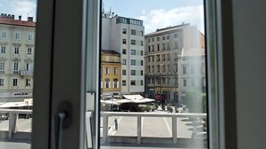 Vista de um horizonte urbano com edifícios altos, uma área para pedestres com mesas ao ar livre e um céu claro.