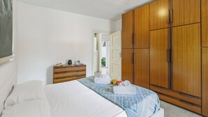 Quarto com cama, guarda-roupa de madeira e cómoda.
