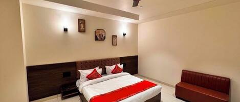 Quarto moderno com uma cama grande, um banco vermelho, ventilador de teto e luminárias fixadas na parede.