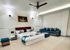 Quarto moderno com cama, sofá e ventilador de teto.