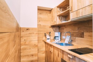 Uma cozinha compacta com armários de madeira, uma cafeteira embutida e uma pia.