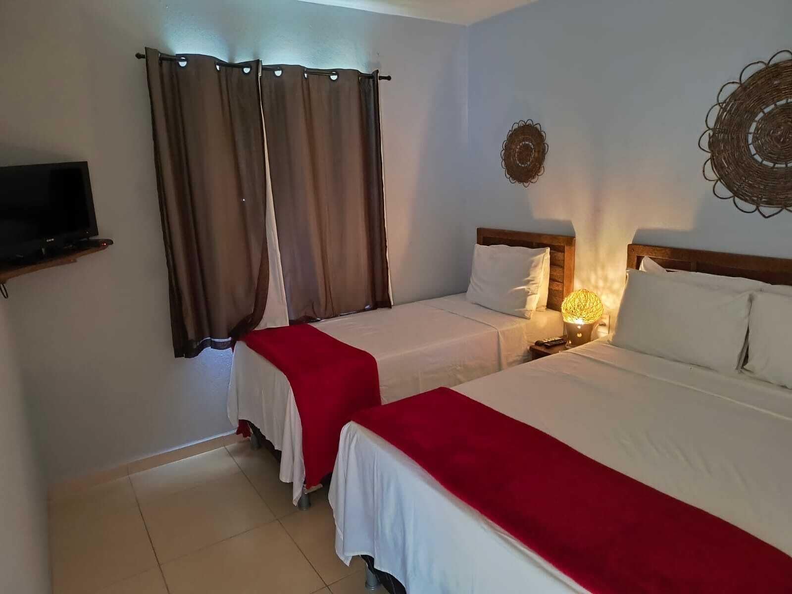Quarto de hotel com duas camas, uma televisão na parede e um ornamento decorativo.