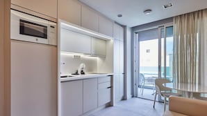 Cozinha moderna com eletrodomésticos embutidos, espaço de jantar com mesa e cadeiras, e varanda com vista.