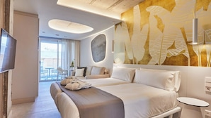 Quarto de hotel moderno com uma cama grande, área de estar, televisão e varanda com vista.