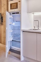 Uma cozinha moderna com micro-ondas embutido, pia de aço inoxidável e armários brancos.