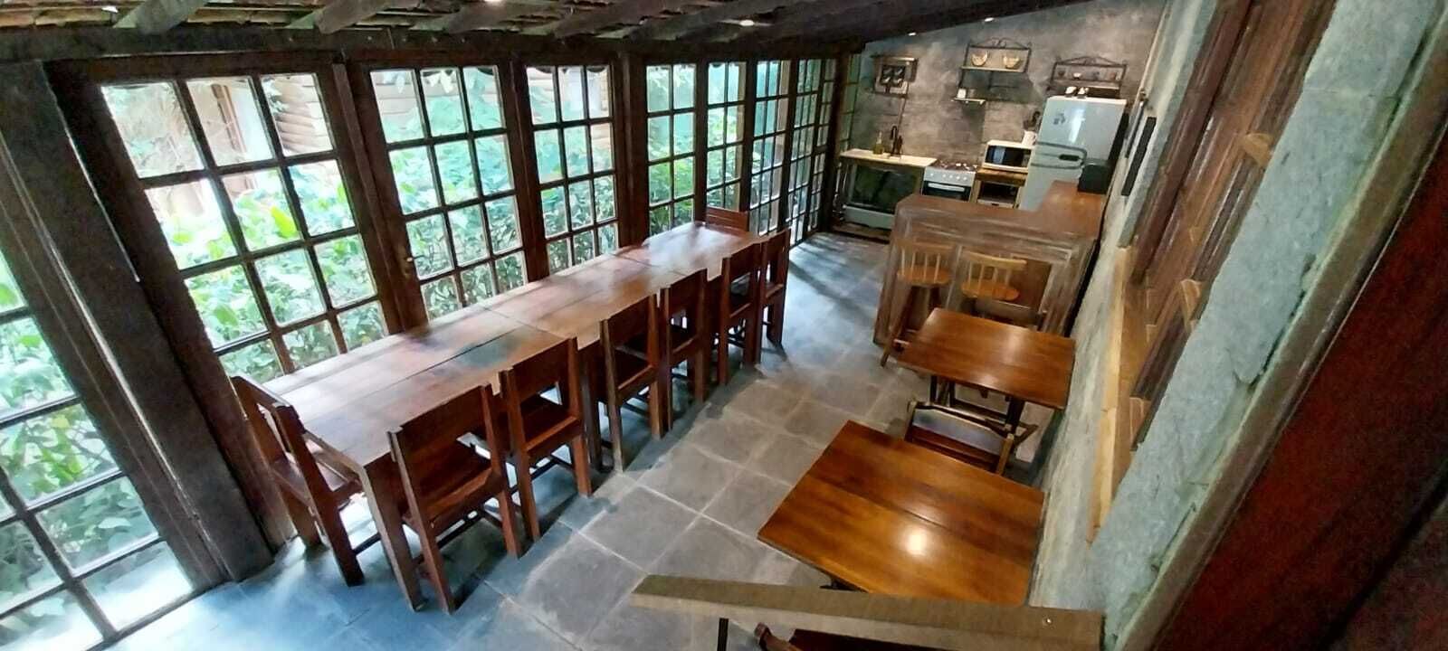 Cozinha com uma mesa de madeira comprida e cadeiras, fogão e geladeira.