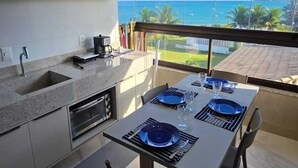 Cozinha moderna com uma grande janela com vista para o oceano, uma área de jantar com mesa posta para dois e vista para o mar.