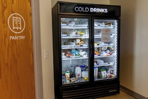 Balcão refrigerado com bebidas e lanches, identificado com a etiqueta 'COLD DRINKS'.
