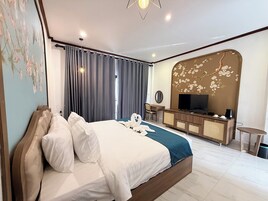 Quarto de hotel com cama grande, escrivaninha com televisão e decoração na parede.