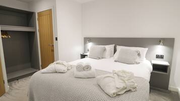 Quarto de hotel com cama, duas mesas de cabeceira, guarda-roupa e espelho.