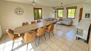 Uma sala de estar ampla com uma mesa de jantar de madeira, várias cadeiras, um sofá e uma lareira.