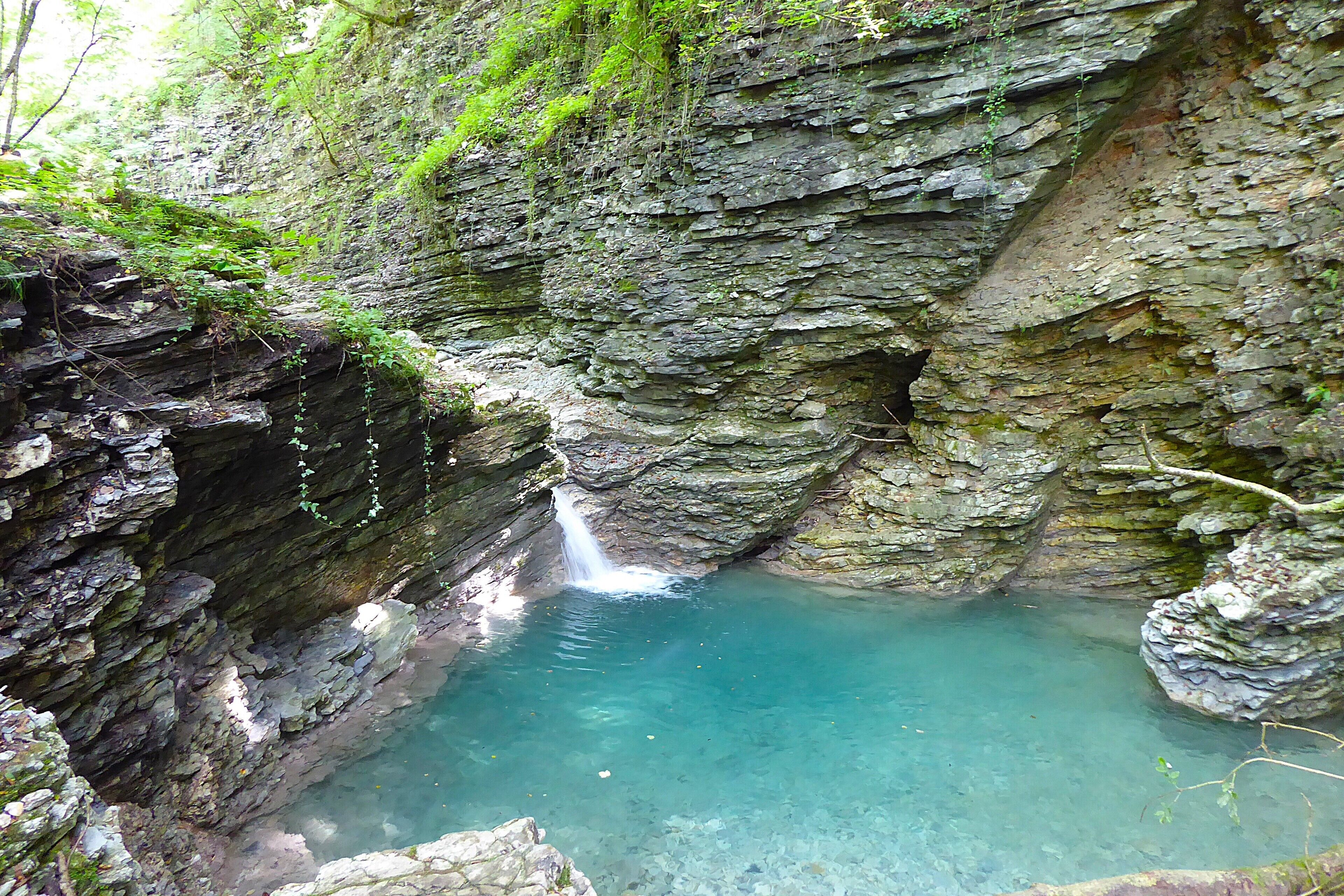 Formação rochosa natural com piscina de águas cristalinas e uma pequena cascata.