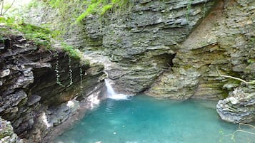 Formação rochosa natural com piscina de águas cristalinas e uma pequena cascata.