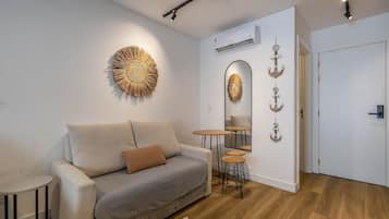 Uma sala de estar moderna com sofá, uma decoração circular na parede, uma mesinha e um espelho com detalhes decorativos.