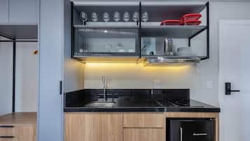 Cozinha moderna com bancada preta, eletrodomésticos de aço inoxidável e adega embutida.