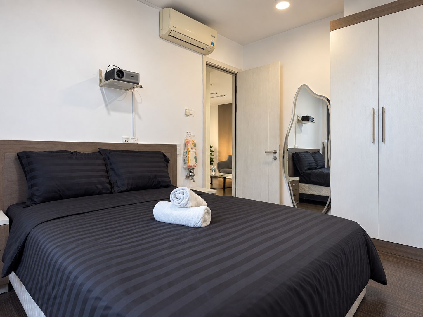 Quarto de hotel com cama, espelho, guarda-roupa e ar condicionado.