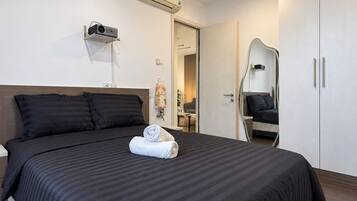 Quarto de hotel com cama, espelho, guarda-roupa e ar condicionado.