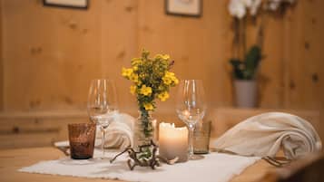 Uma mesa de jantar com uma vela, um vaso de flores amarelas e dois copos de vinho.