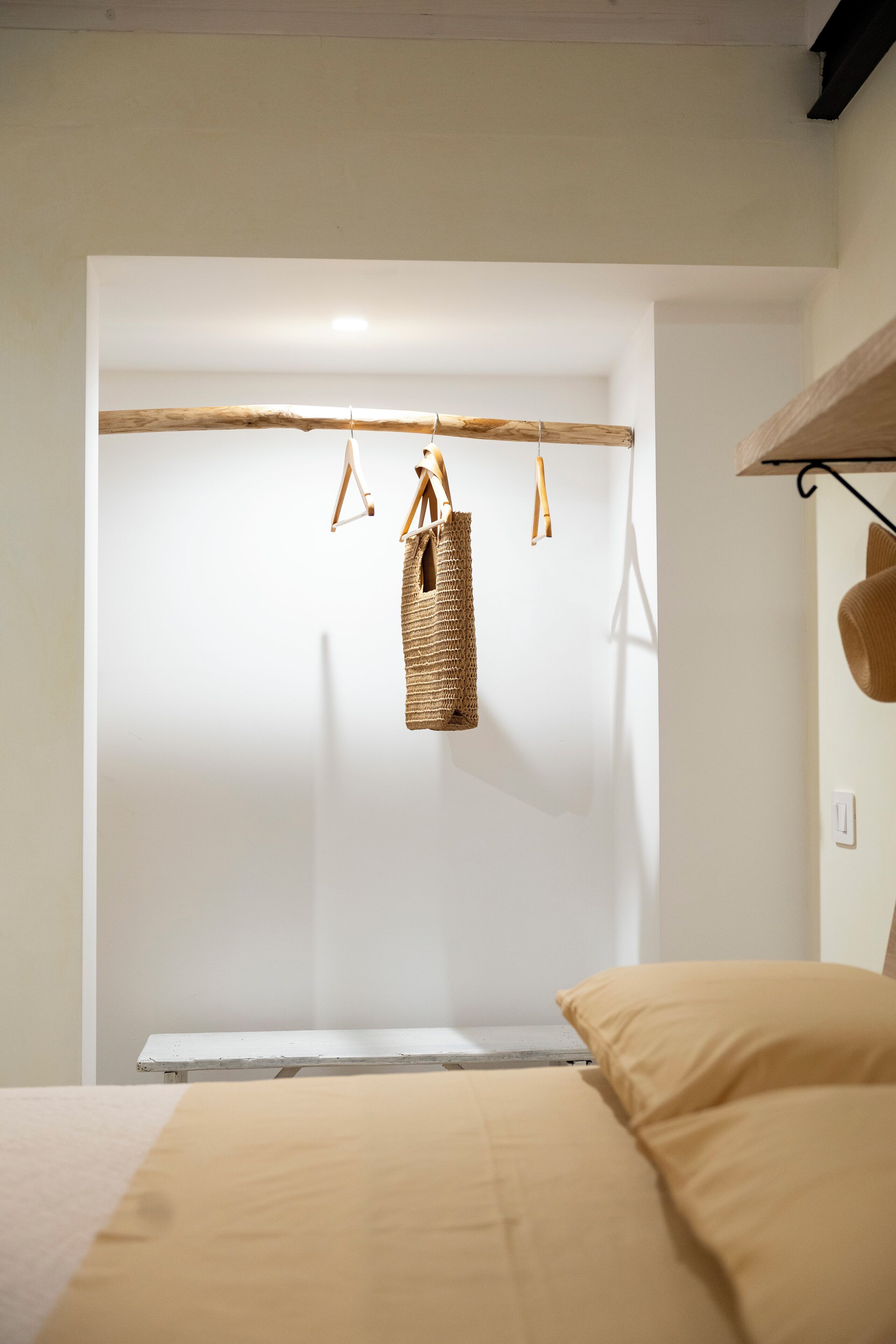 Quarto com cama, um cesto pendurado e prateleira com abajur.