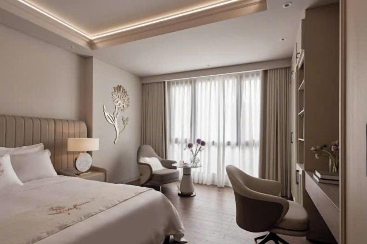 Quarto de hotel moderno com uma cama grande, área de estar e vista para a cidade.