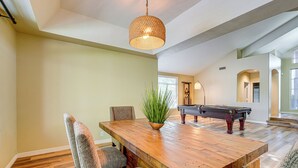 Uma área de jantar ampla com mesa de madeira, cadeiras e mesa de bilhar.