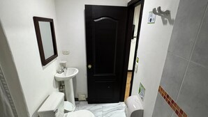 Uma casa de banho pequena com sanita, lavatório e espelho.