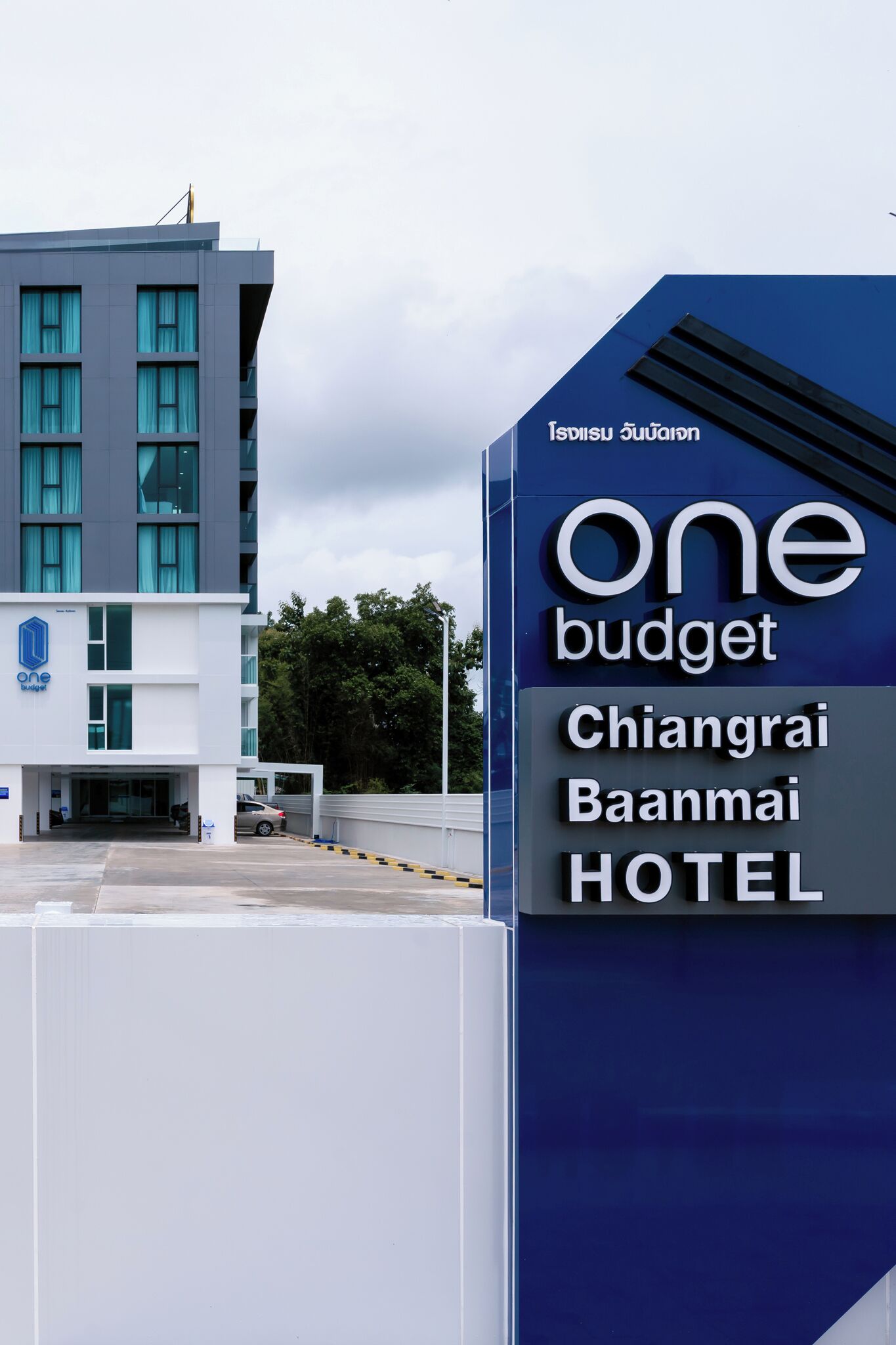 Entrada moderna de hotel com uma placa de destaque para 'One Budget Chiangrai Baanmai Hotel'.