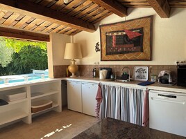 Uma cozinha com teto de madeira, uma pintura grande, uma pia e uma máquina de lavar louça.