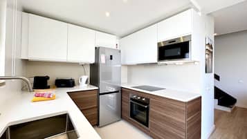 Um micro-ondas, uma cafeteira/bule, utensílios de cozinha