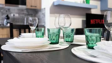 Mesa de jantar posta com copos verdes e pratos brancos, com o logotipo da Netflix ao fundo.