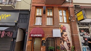 Um edifício de dois andares com toldo vermelho identificado como "DIL'S APARTMENTS".