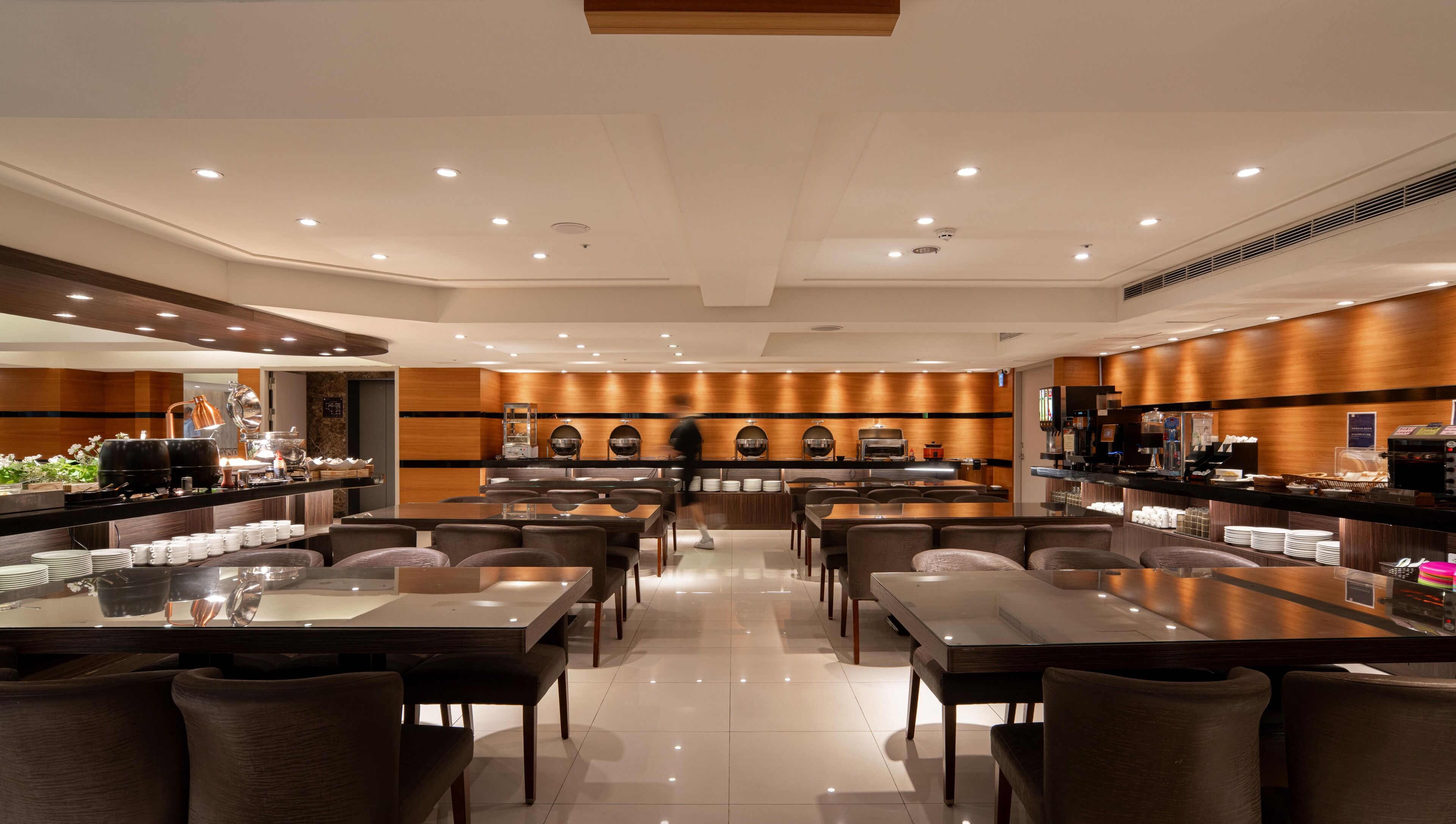 Restaurante moderno com bar central, várias áreas de estar e piso lustroso.