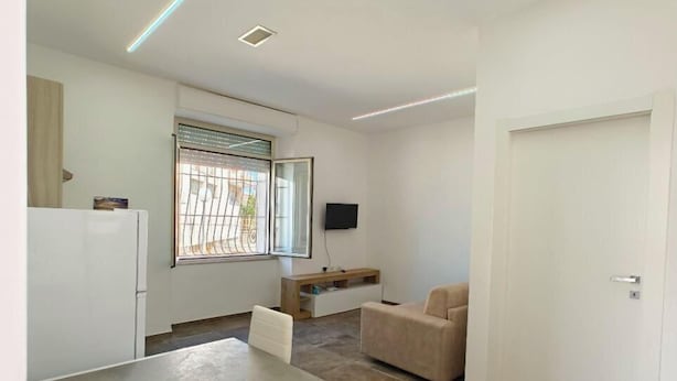 Uma cozinha moderna com área de jantar, uma TV fixada na parede e uma porta que dá para outro cômodo.