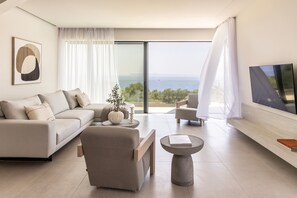 Uma sala de estar moderna com sofá, poltrona, mesa de centro e televisão de tela plana.