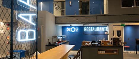 Uma área de bar moderna com um letreiro de neon, um balcão e assentos.