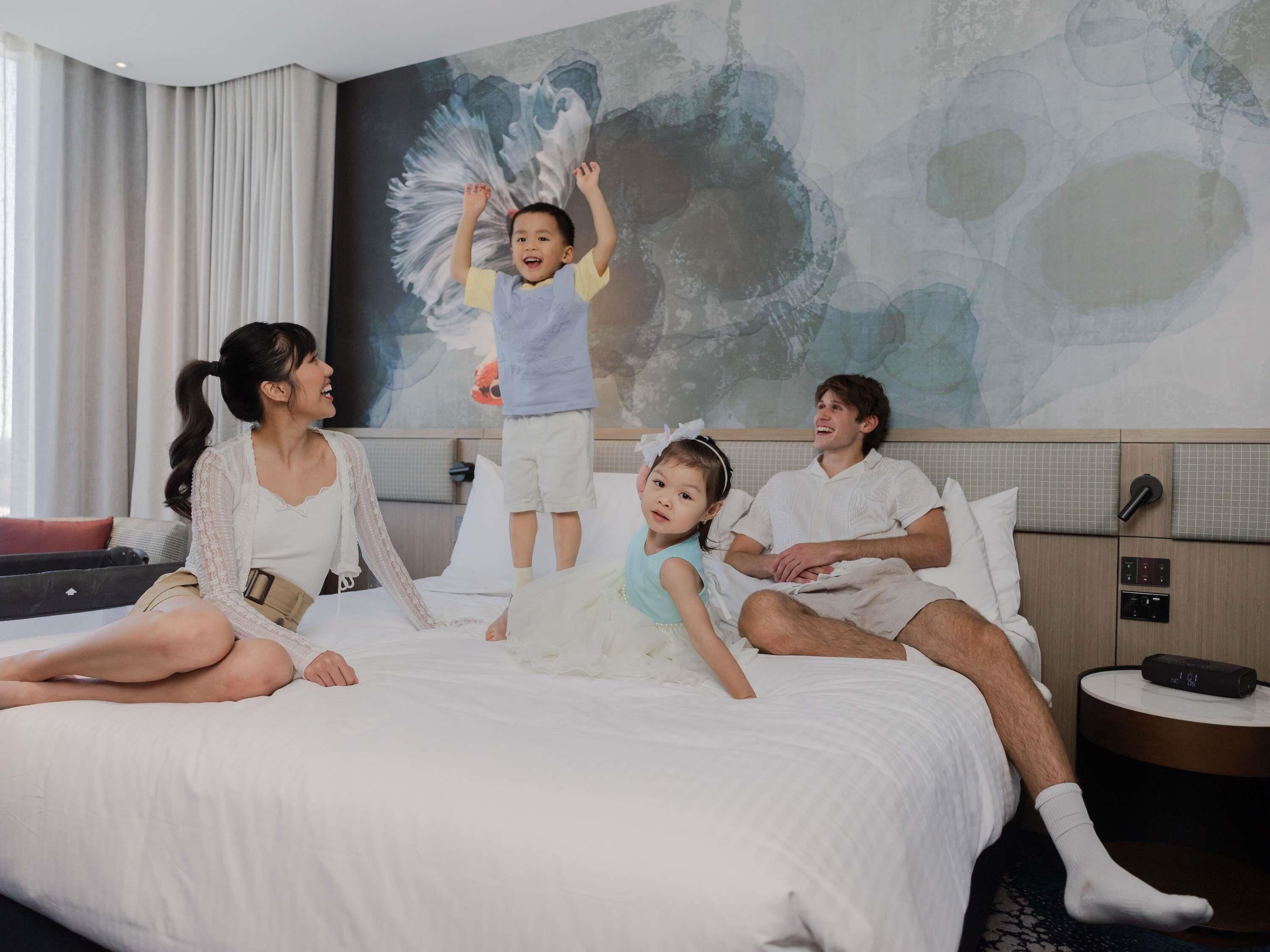 Quarto de hotel com uma cama grande, uma mesinha de cabeceira e uma parede com um mural floral.