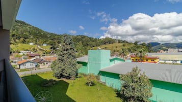 Bairro residencial com casas, um edifício verde e uma colina ao fundo.