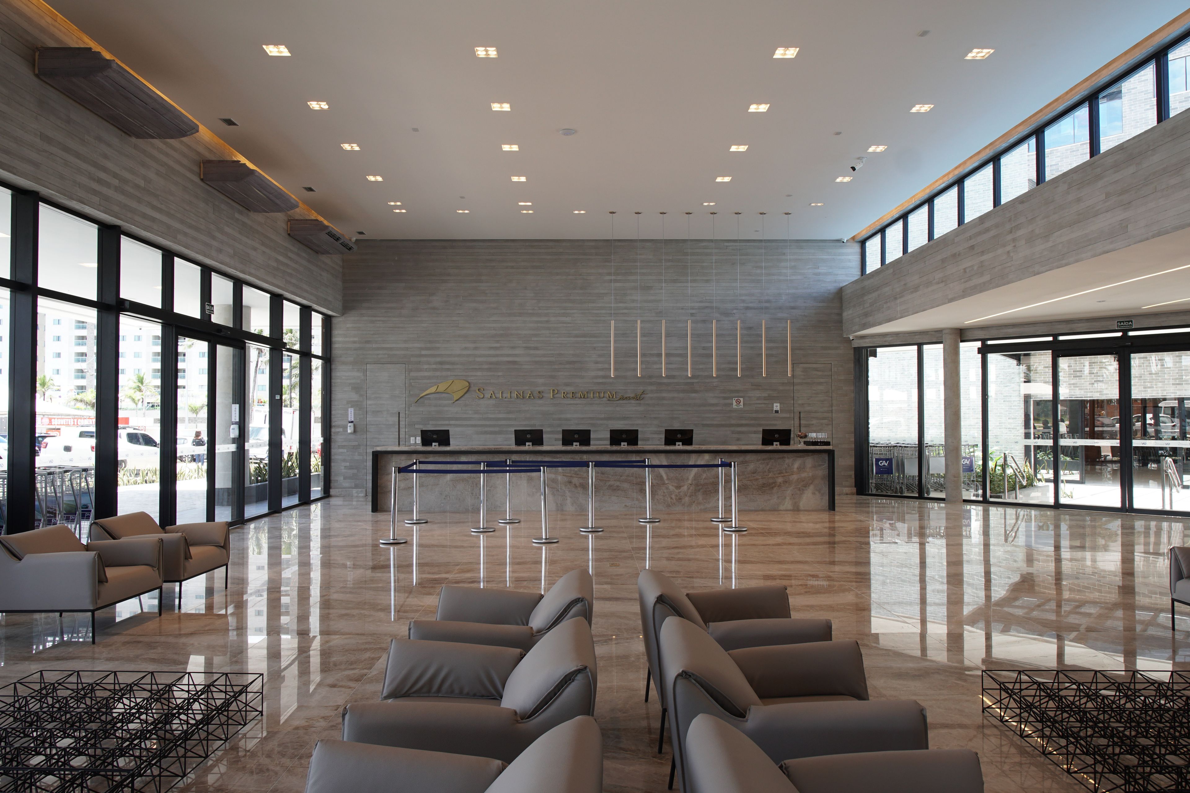 Um hall espaçoso com balcão de recepção, área de estar e grandes janelas com vista para o exterior.