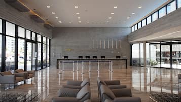 Um hall espaçoso com balcão de recepção, área de estar e grandes janelas com vista para o exterior.