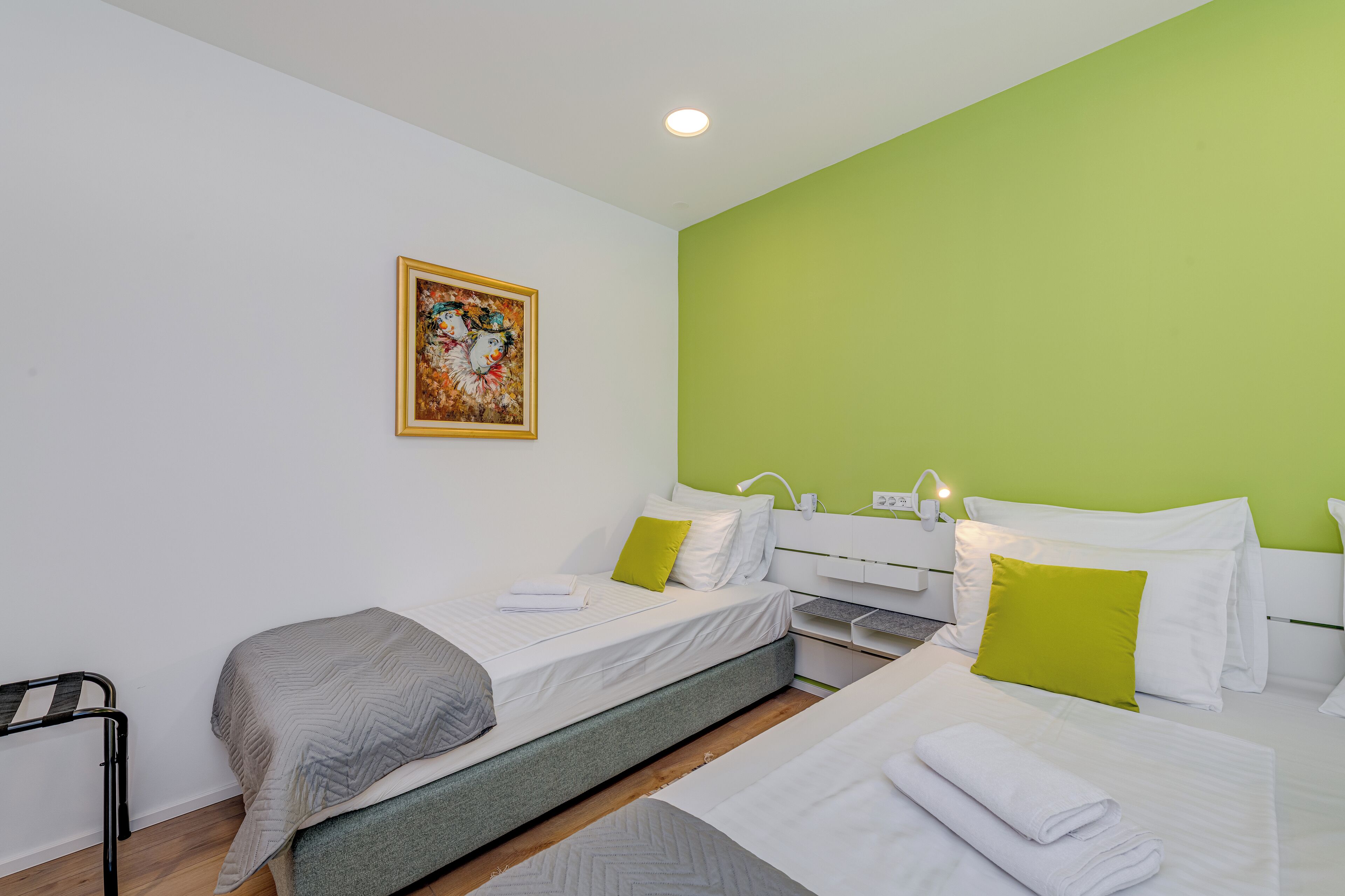 Quarto de hotel com cama, mesa de cabeceira, abajur e um quadro na parede.