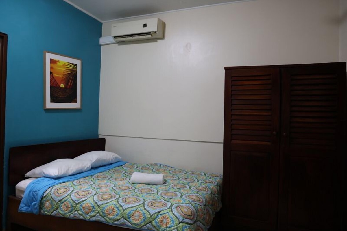 Quarto com cama, ar-condicionado fixado na parede, quadro emoldurado e armário.