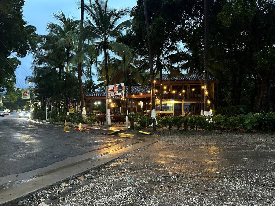 Um edifício com telhado de azulejos, rodeado de palmeiras, e uma placa que indica um restaurante.